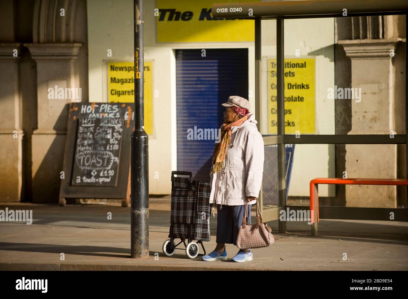 An old lady waiting for a bus at a bus shelter, London Southwark Stock ...