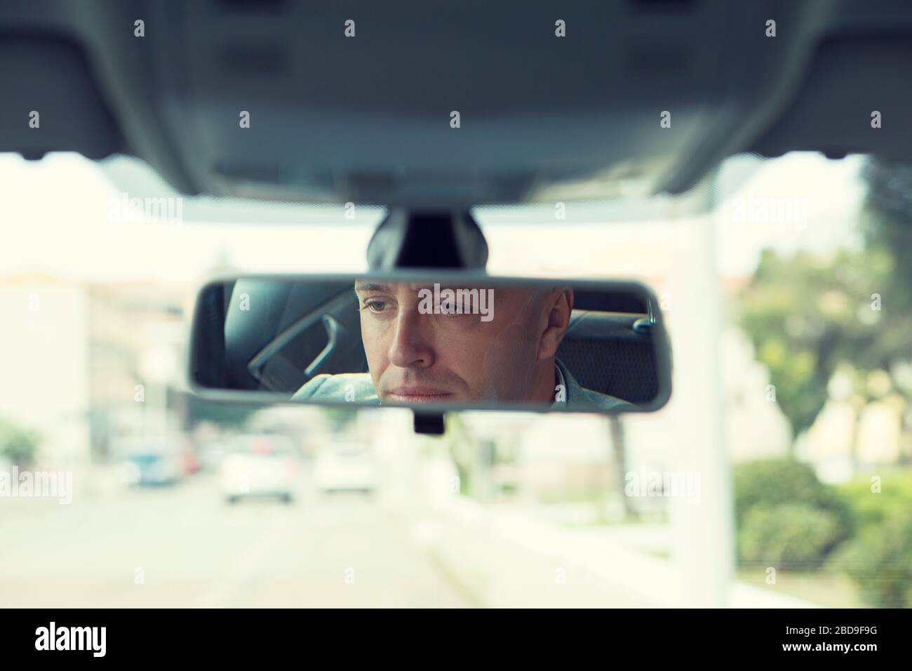 Closeup portrait serious young man driver reflection in rear view ...