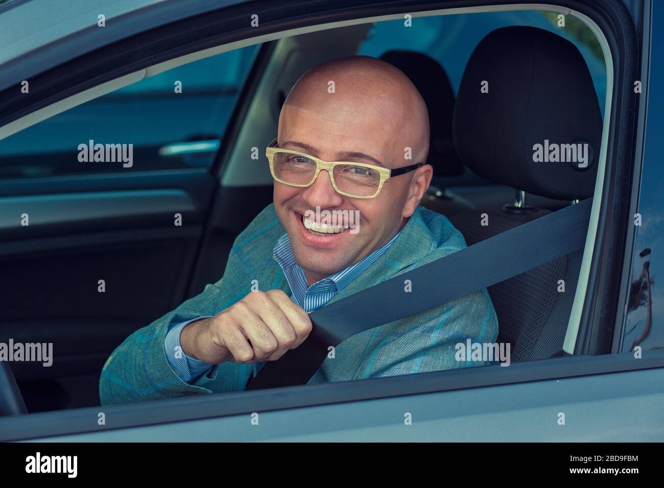 Handsome man smiling looking at camera in his car asking showing you to ...
