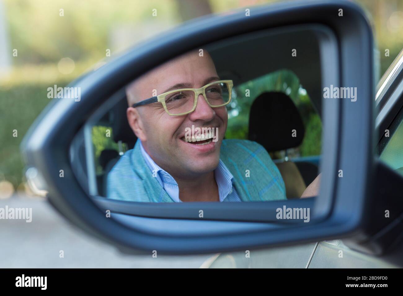 Happy with my car choice. Portrait young man driver reflection in car ...