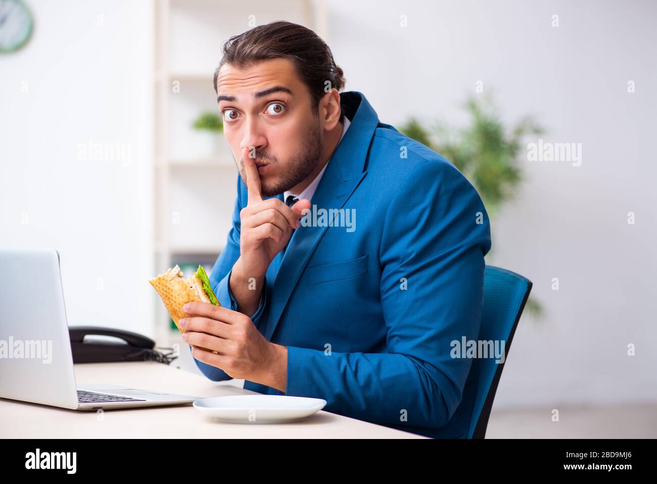 Young employee having breakfast at workplace Stock Photo - Alamy