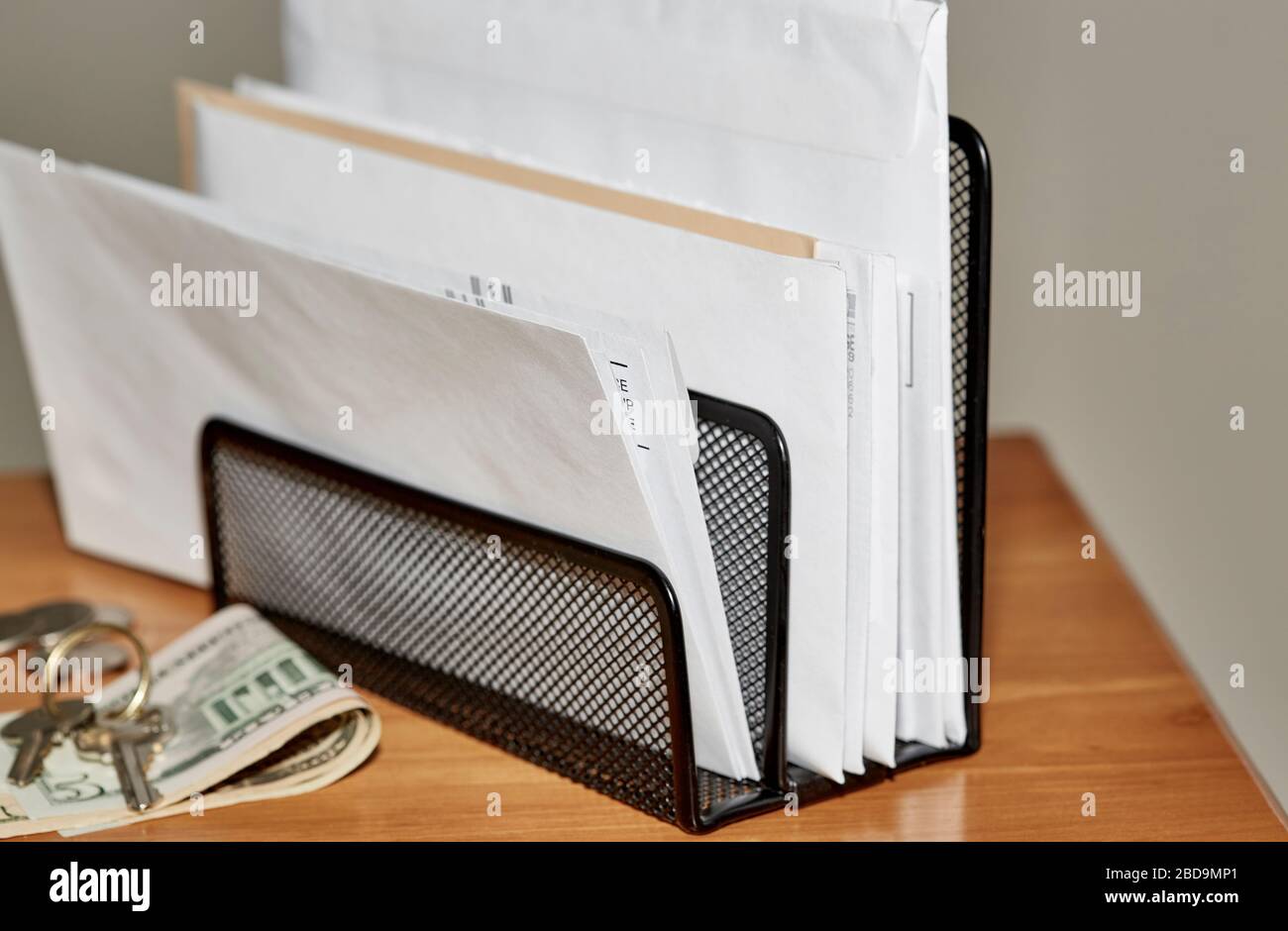 Stack of open and unopened envelopes in a desk organizer with keys ...
