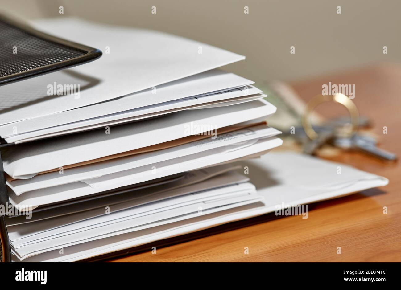 Stack of open and unopened envelopes in a desk organizer with keys ...