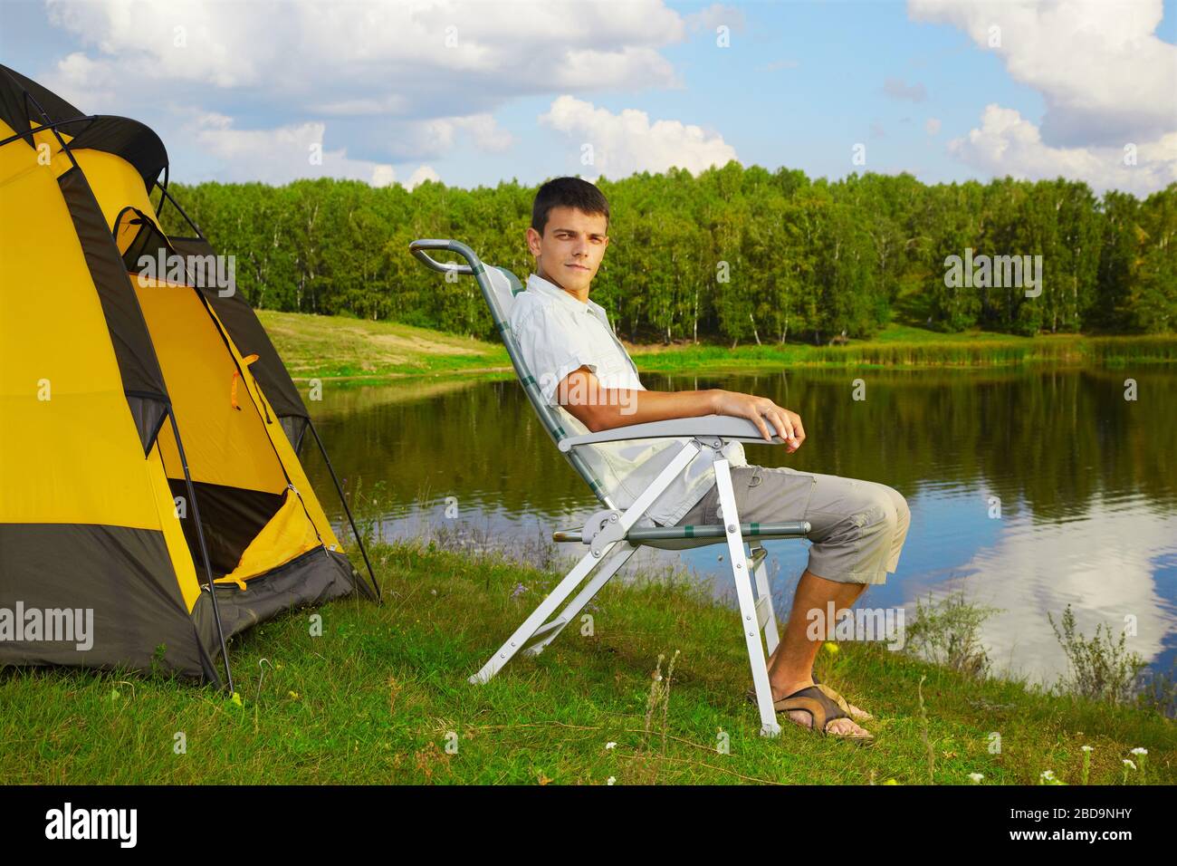 summer outdoor portrait of handsome man sitting in folding chair near ...