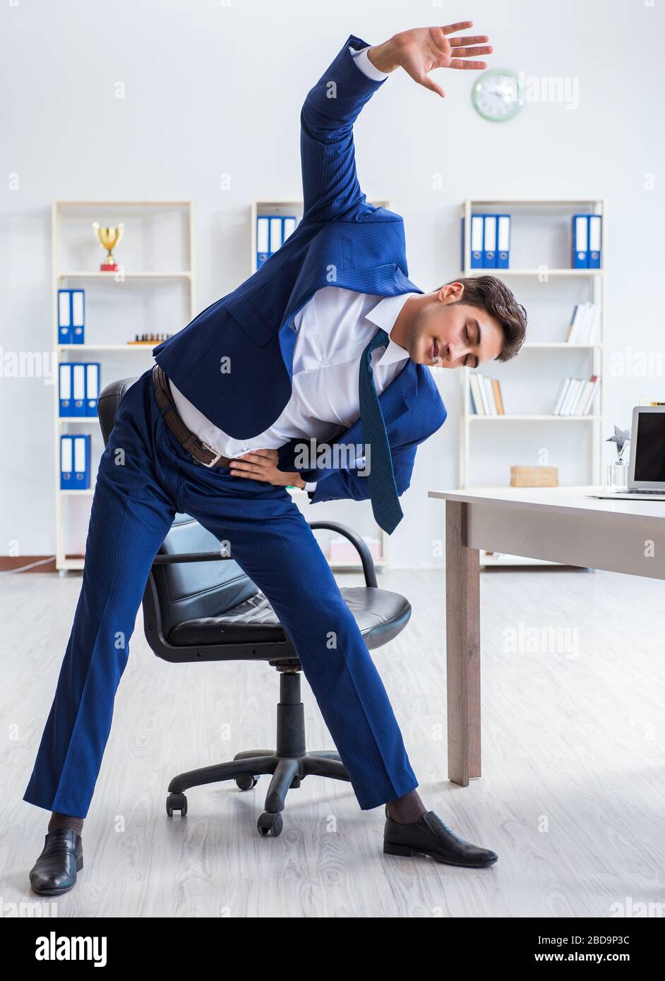 The young businessman doing sports stretching at workplace Stock Photo ...