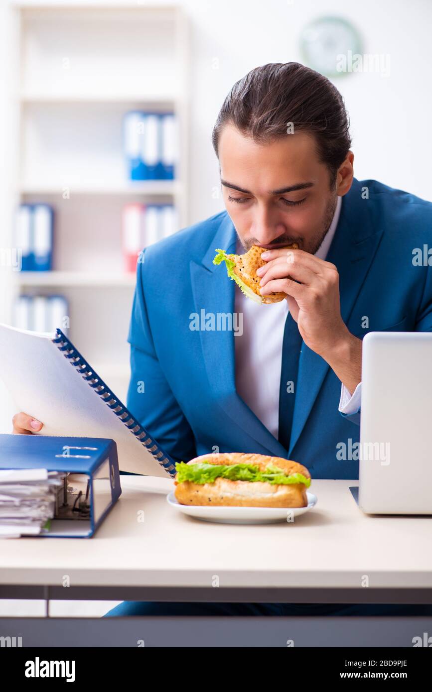 Young employee having breakfast at workplace Stock Photo - Alamy