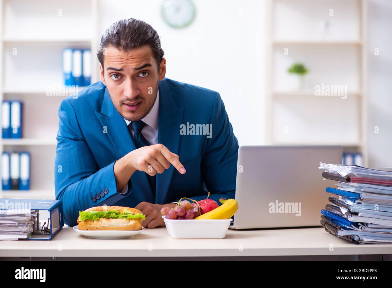 Young employee having breakfast at workplace Stock Photo - Alamy