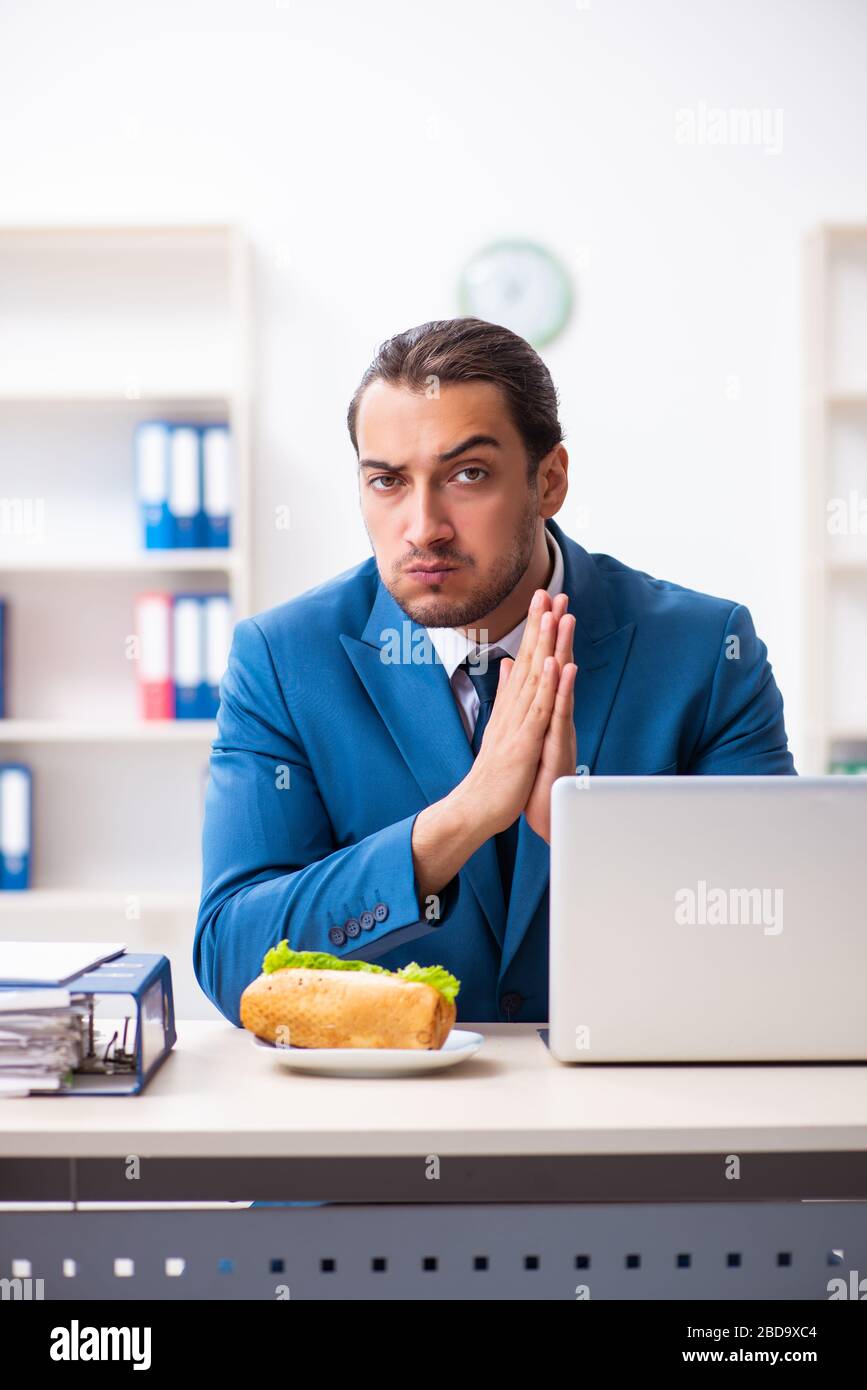 Young employee having breakfast at workplace Stock Photo - Alamy