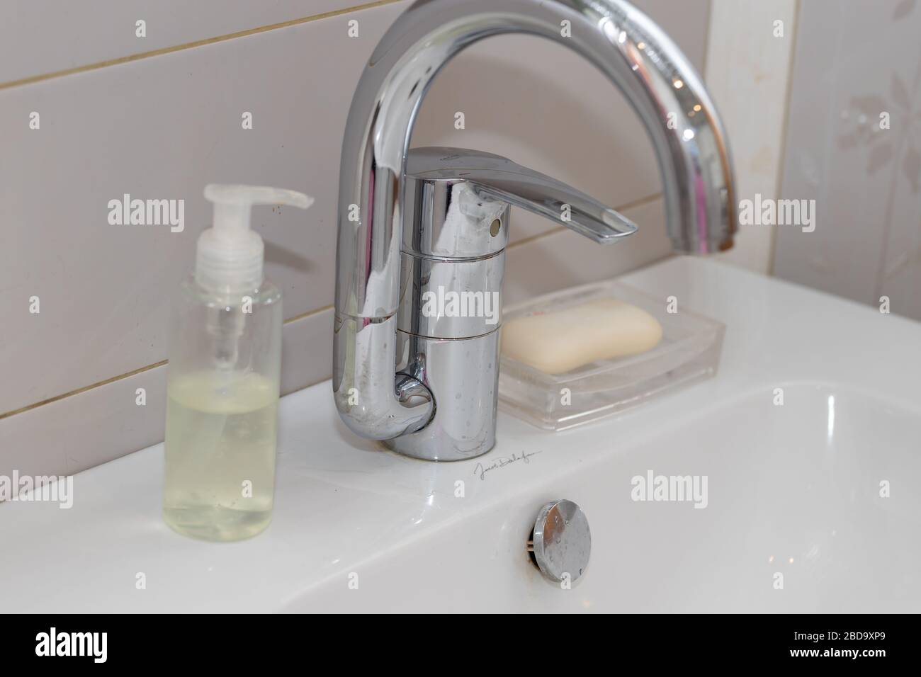 Modern hand wash basin. Solid tabletop surface and gray tile wall ...