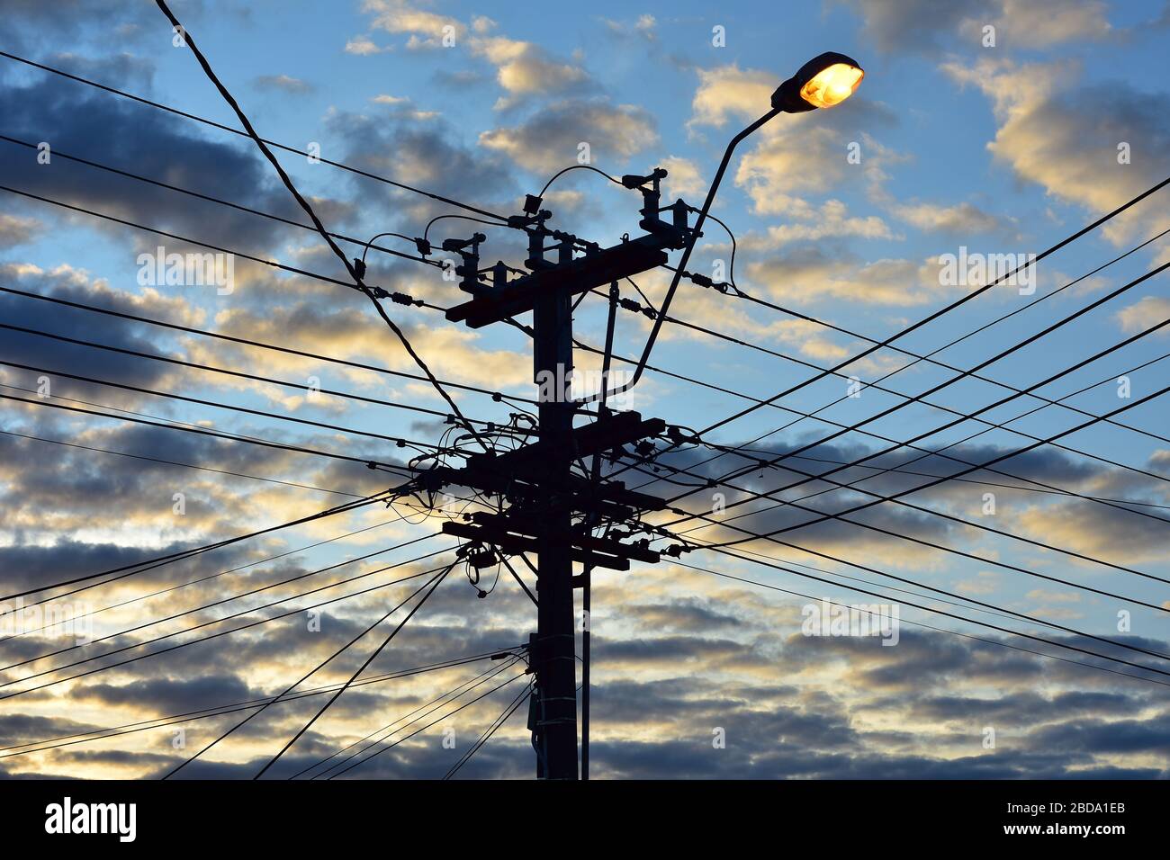 Power grid intersection silhouette with bright street light and sunset ...