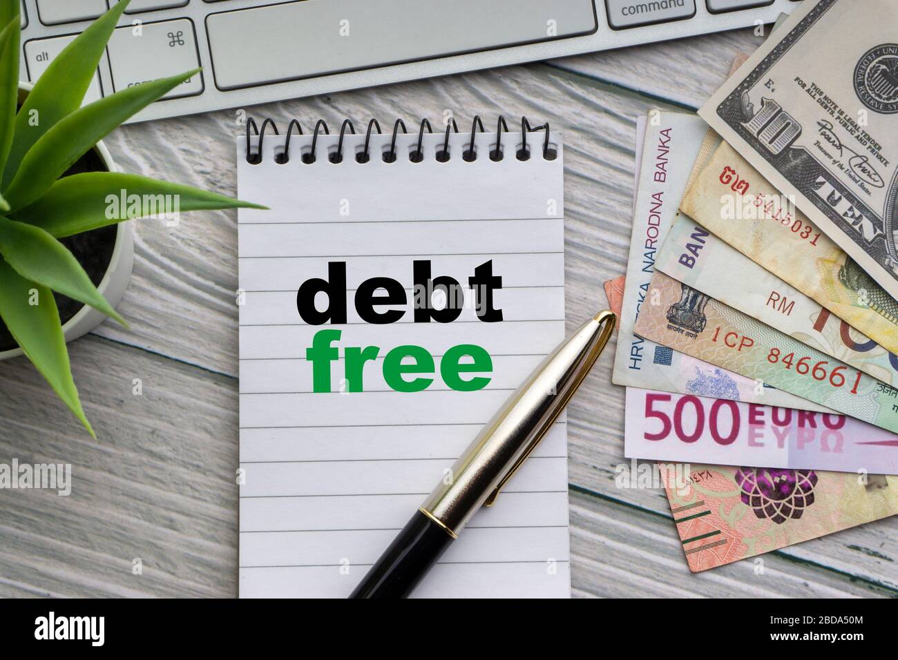 DEBT FREE text with notepad, keyboard, decorative vase, fountain pen ...