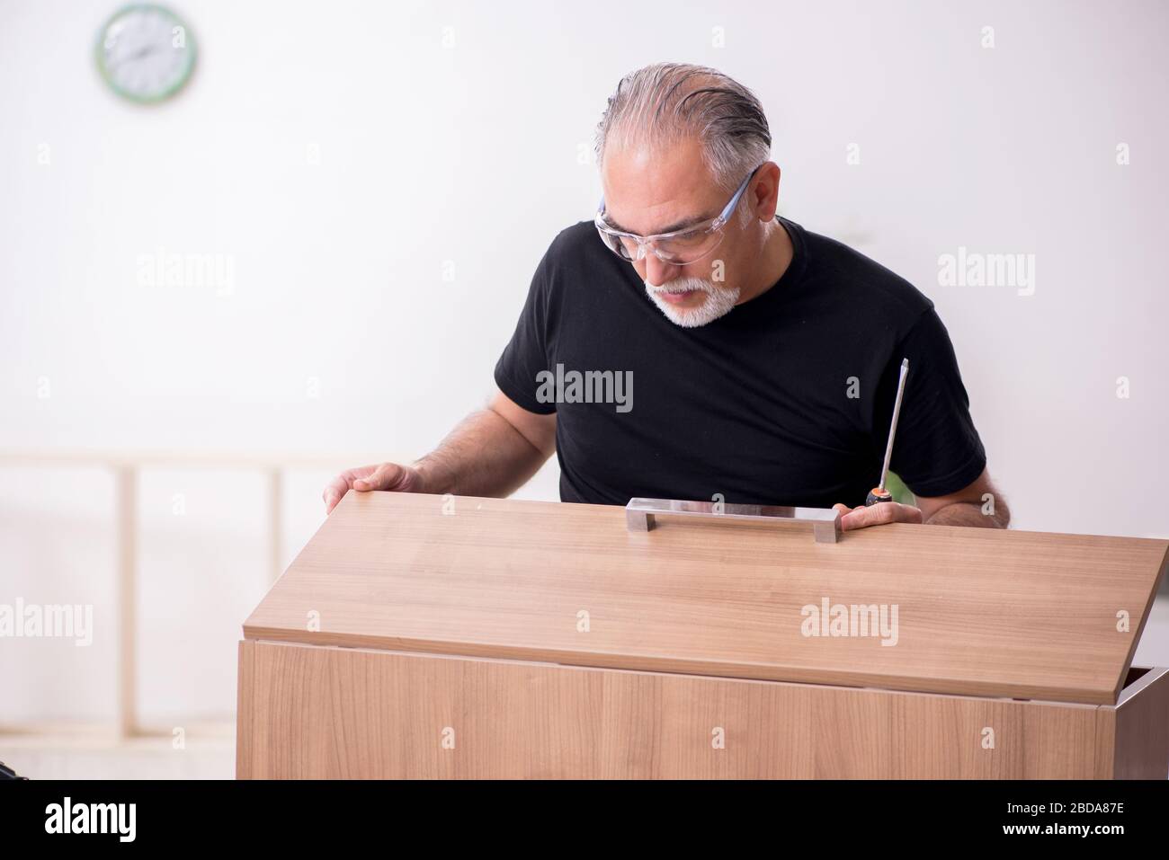 Old carpenter working indoors on furniture Stock Photo - Alamy