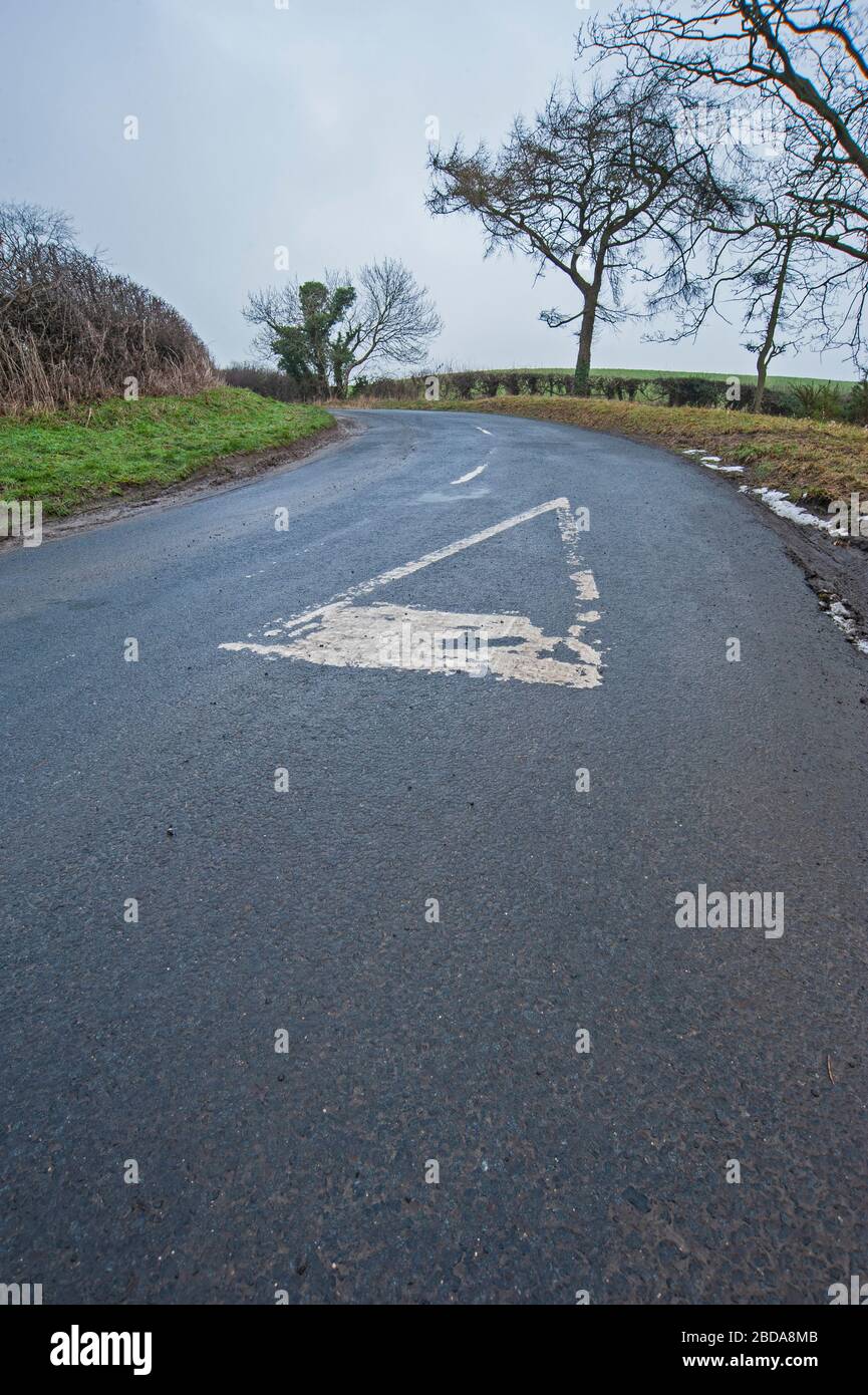 Road in rural countryside landscape with warning sign heading round a ...