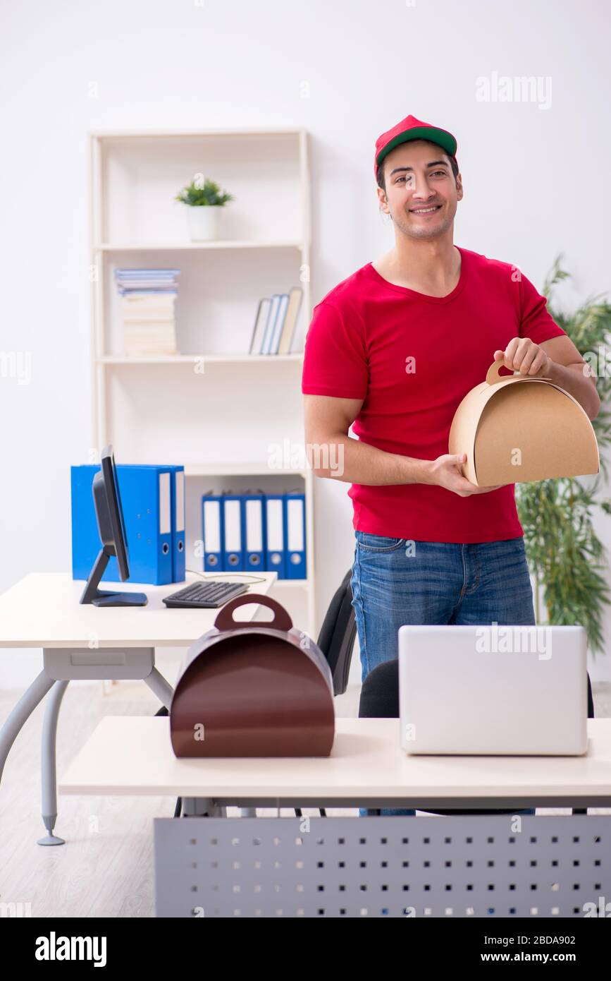Young courier delivering cake to the office Stock Photo - Alamy