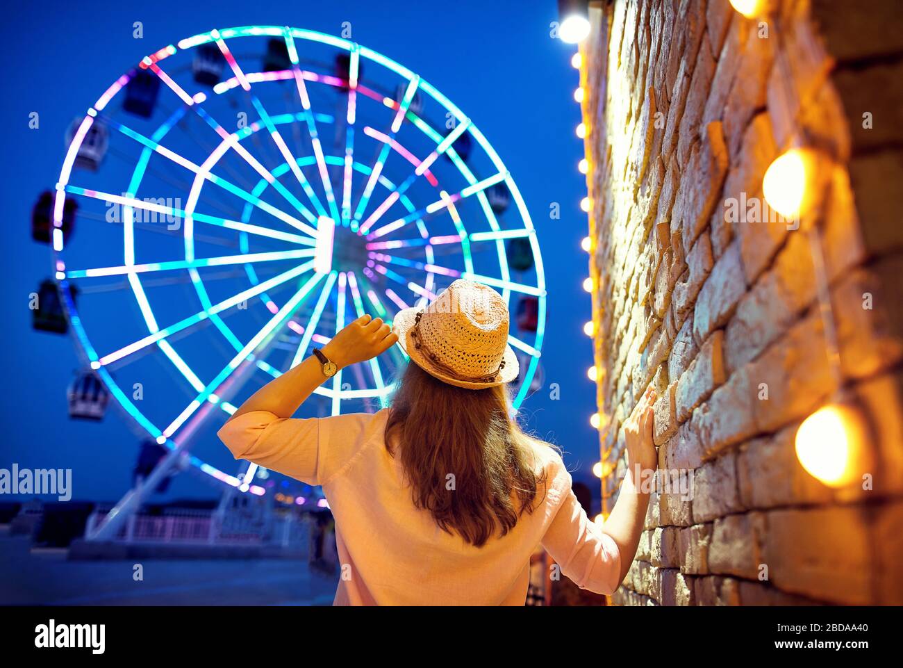 Tourist woman in hat looking at glowing Ferris wheel at night Stock ...