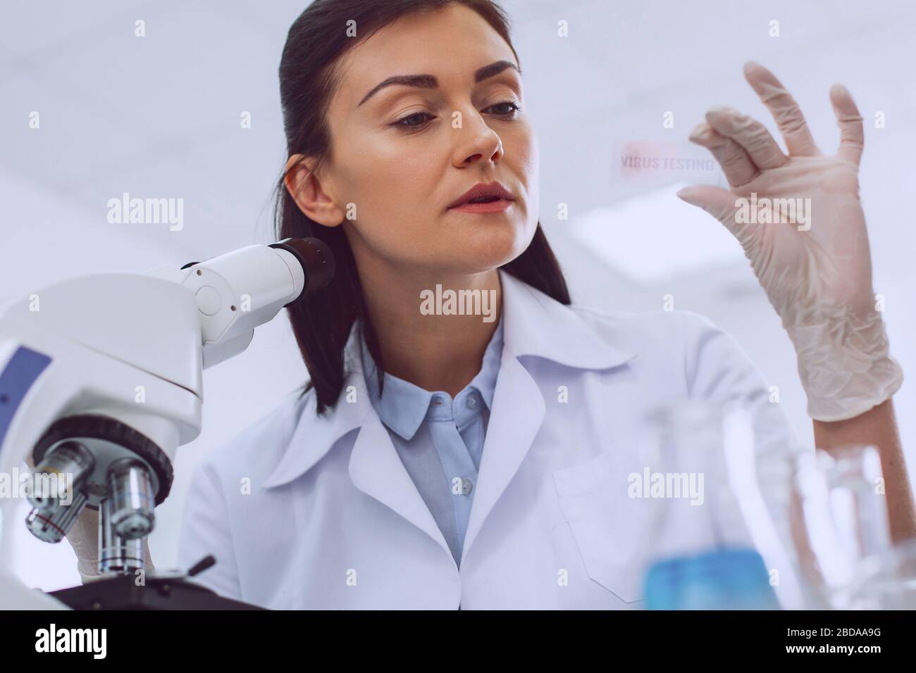 Serious lab worker holding a test sample Stock Photo - Alamy