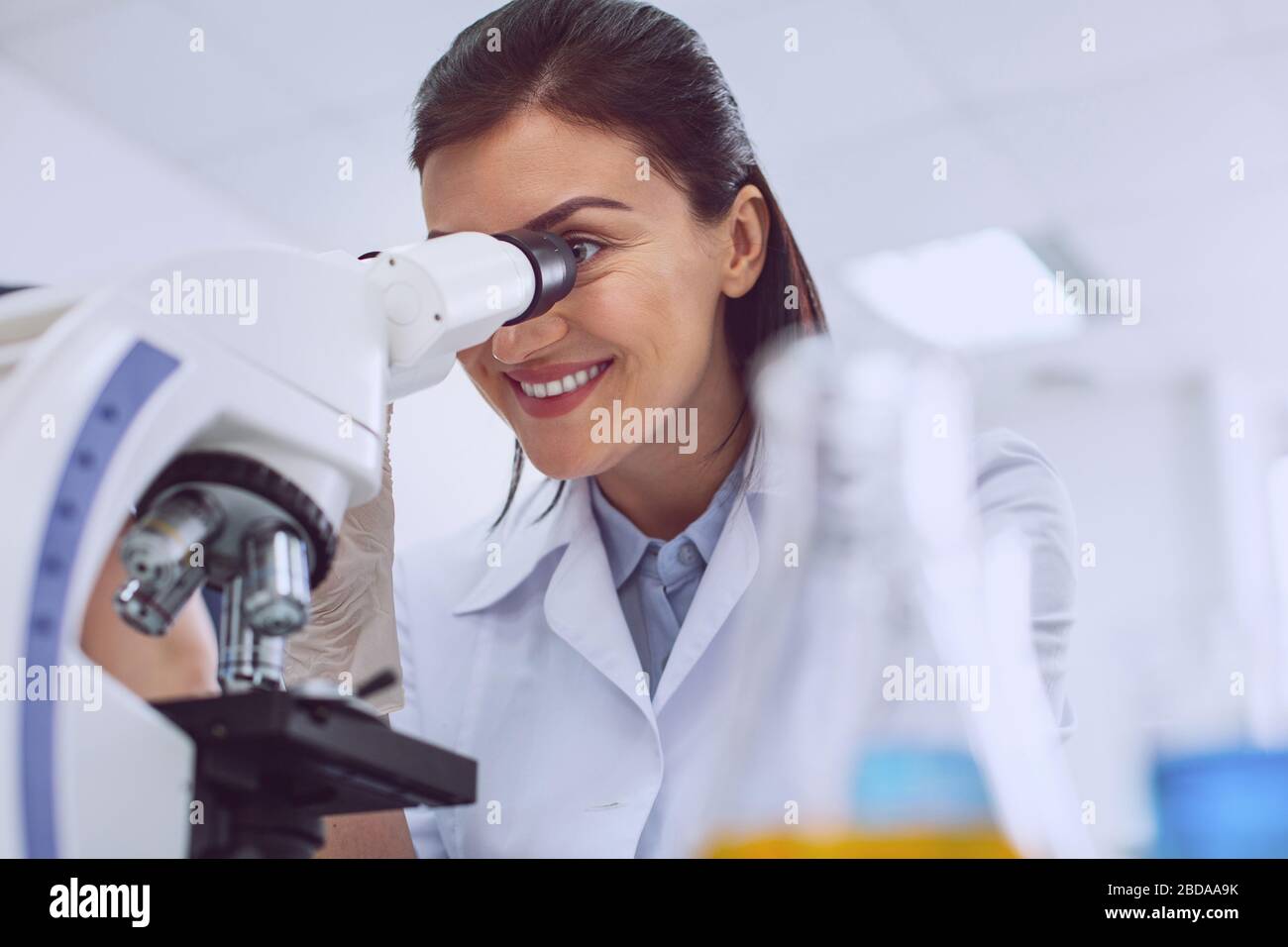 Joyful female researcher looking into the microscope Stock Photo - Alamy