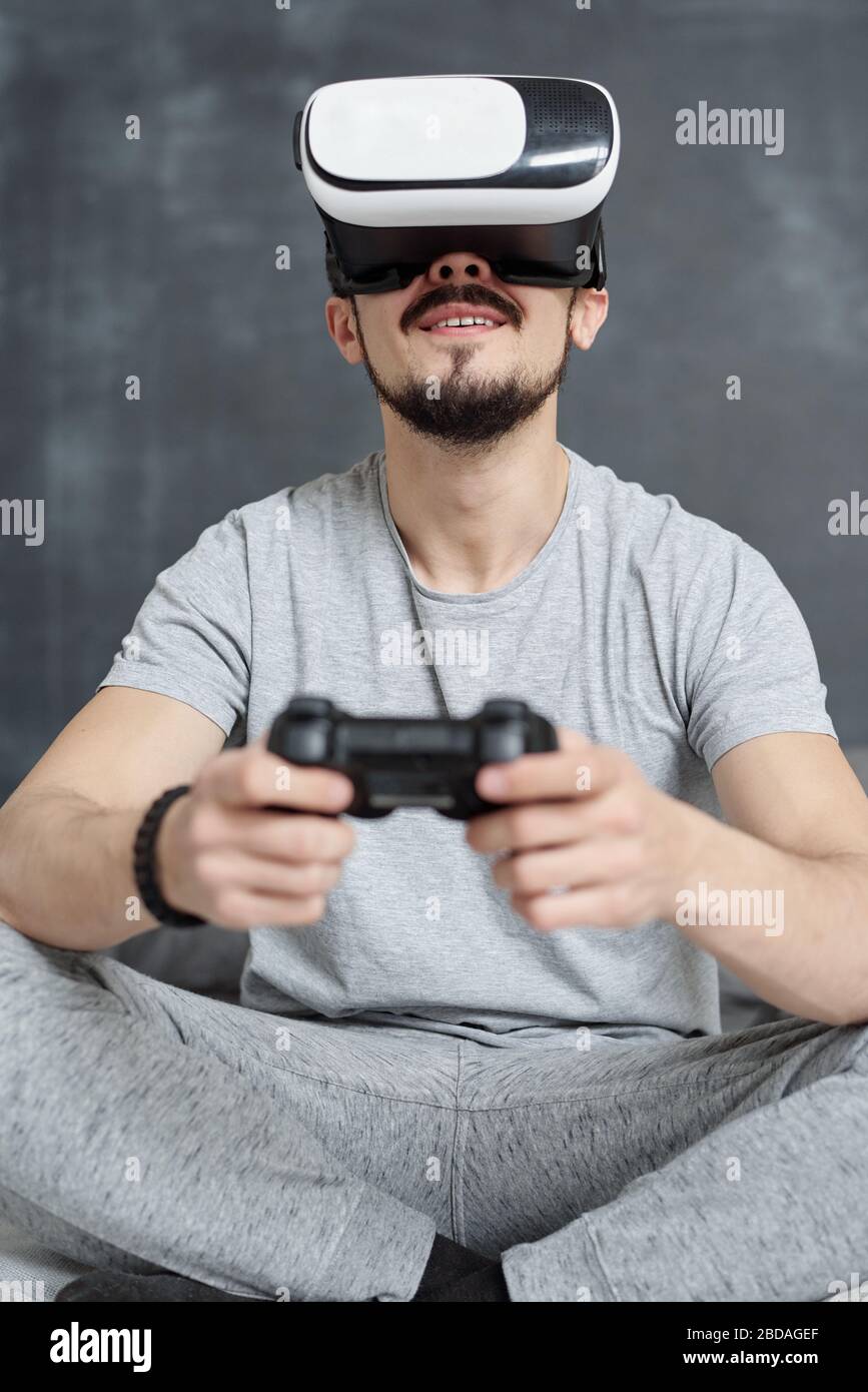 Below view of bearded man in homewear excited about virtual video game ...