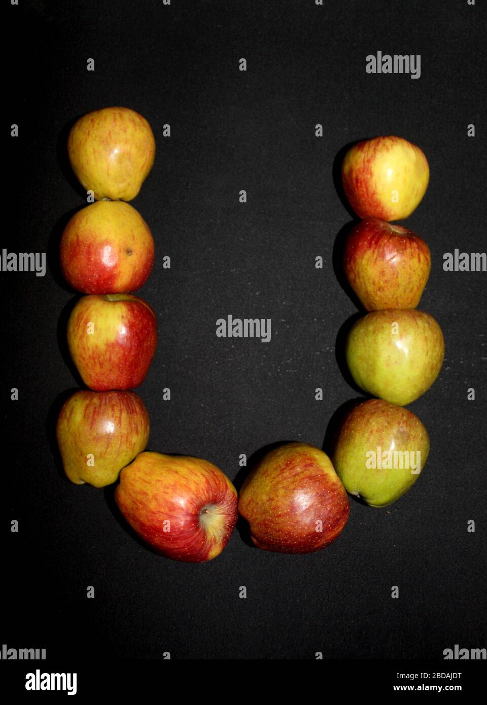 Colorful fresh apples letter alphabet photographed against a black ...