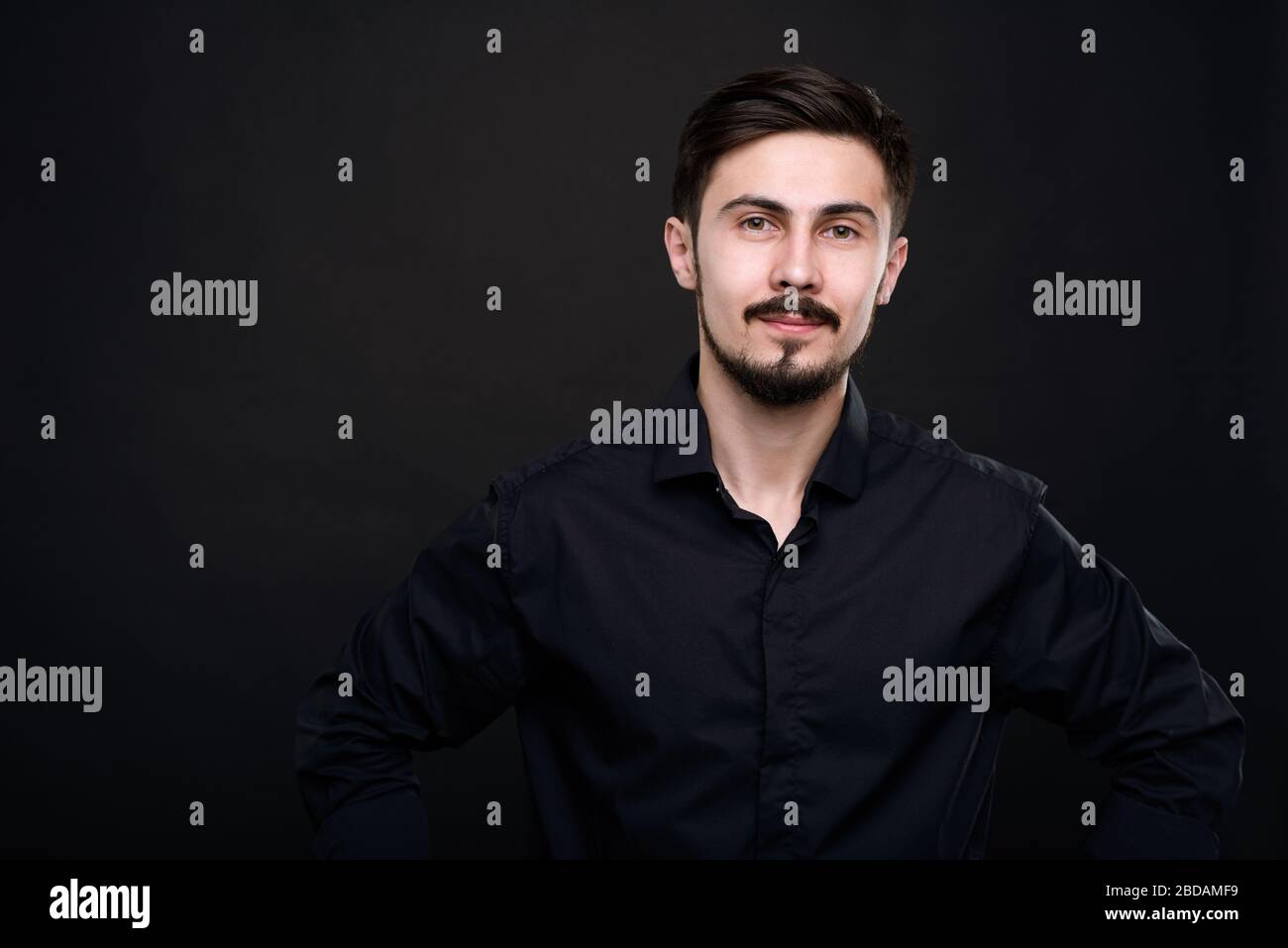 Portrait of content handsome young man with mustache and beard standing ...