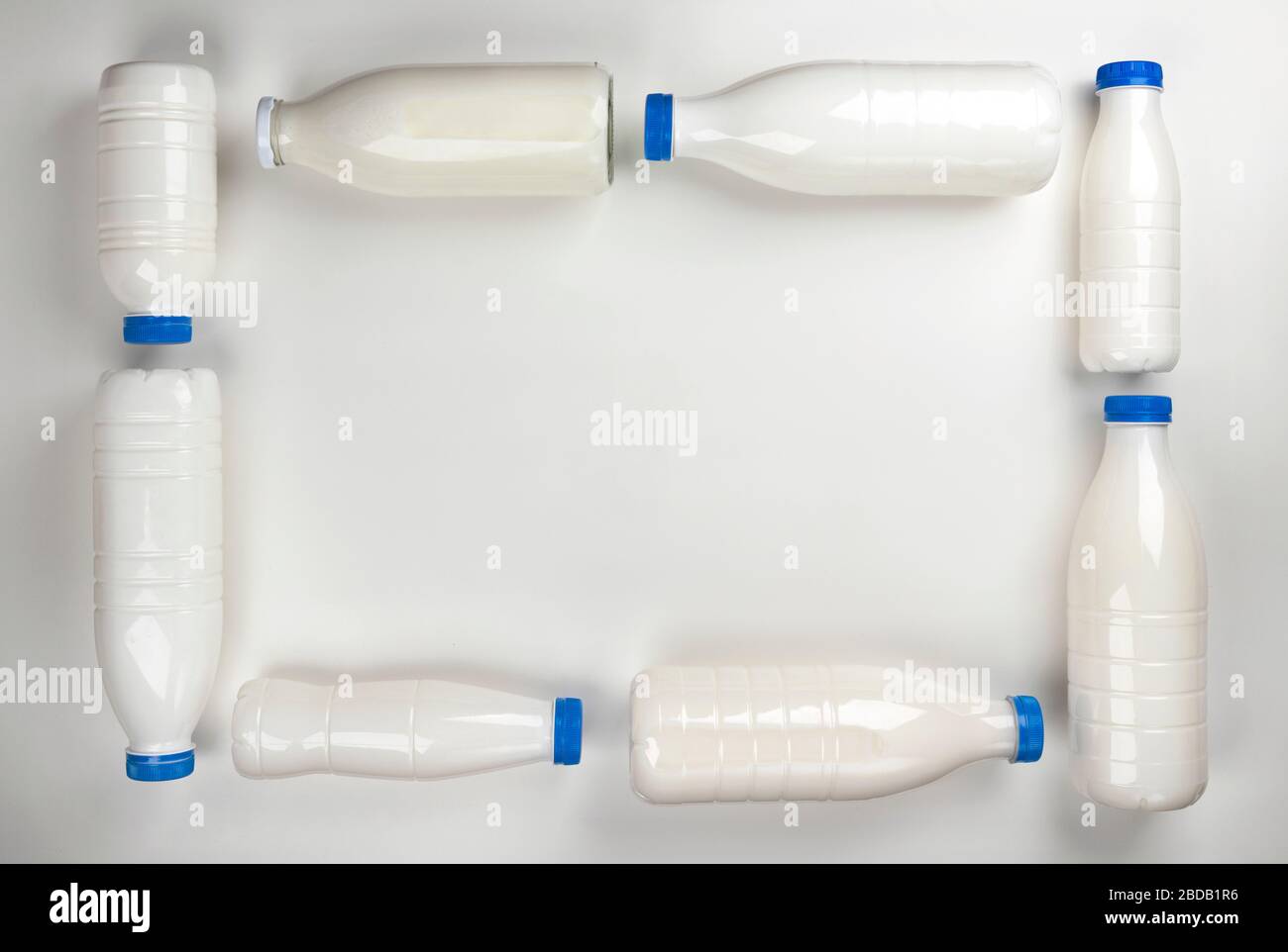 Frame made of bottles for milk and yogurt on white background, top view ...