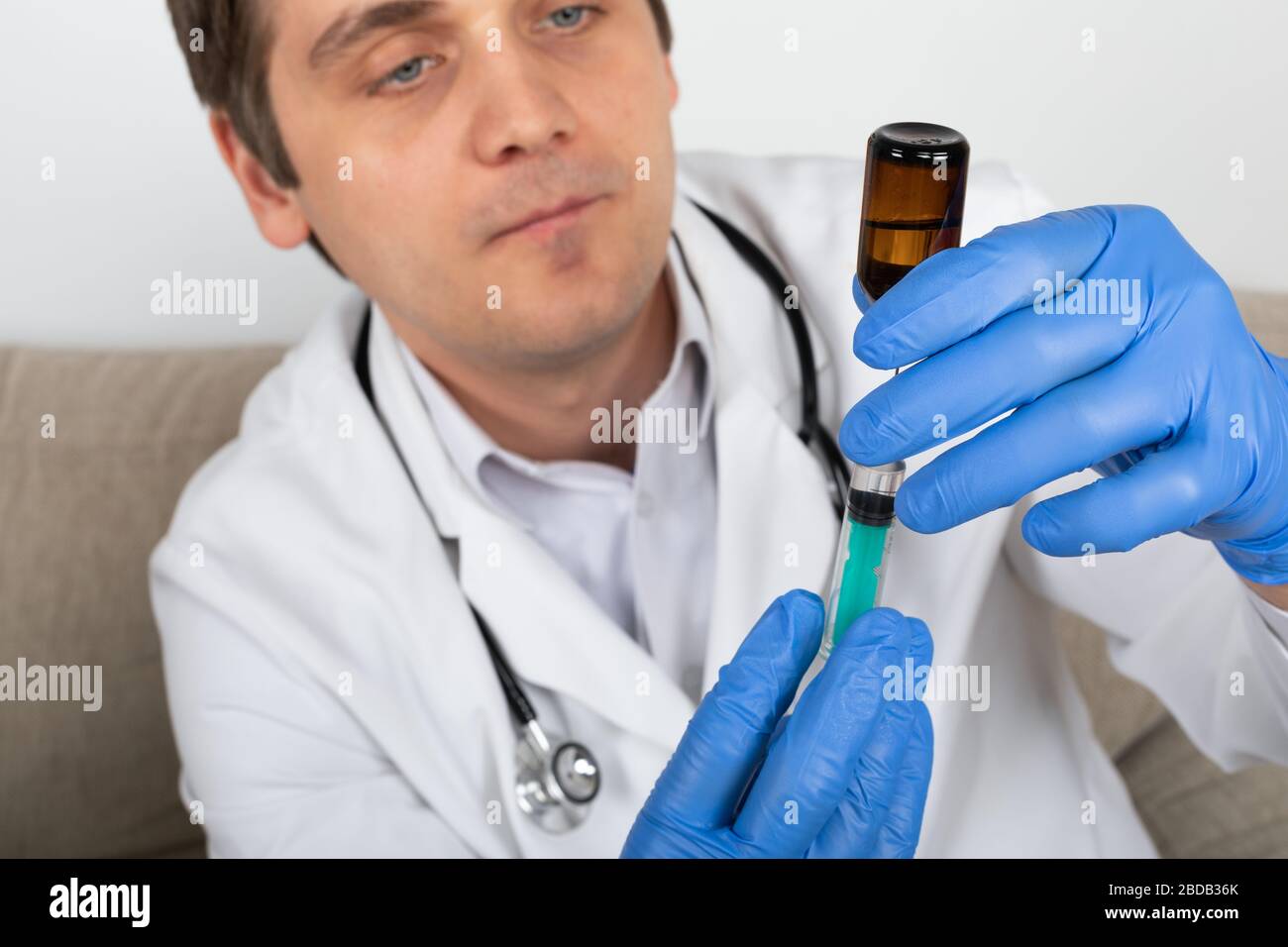 Handsome male doctor holding a bottle with liquid medication and ...