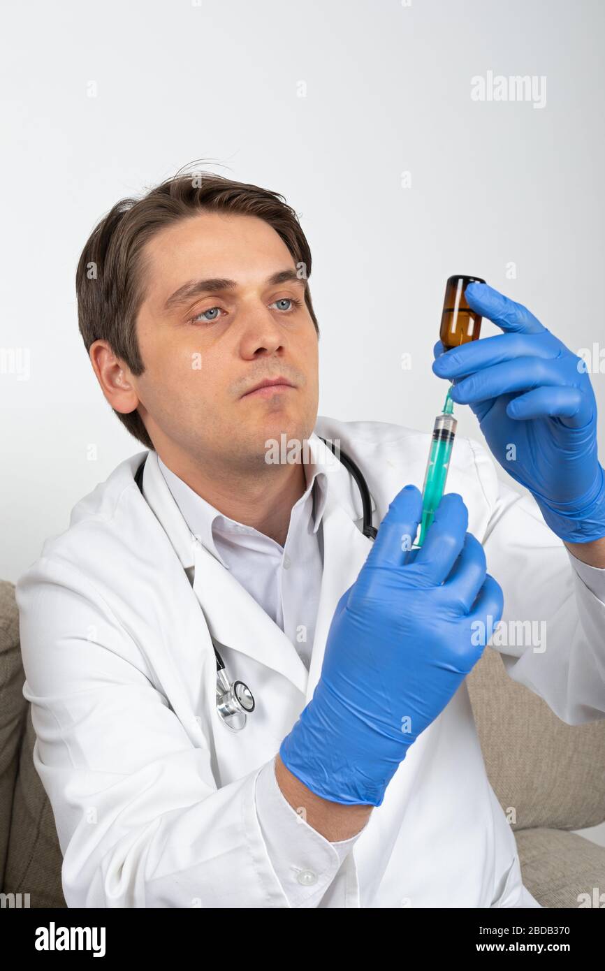 Handsome male doctor holding a bottle with liquid medication and ...