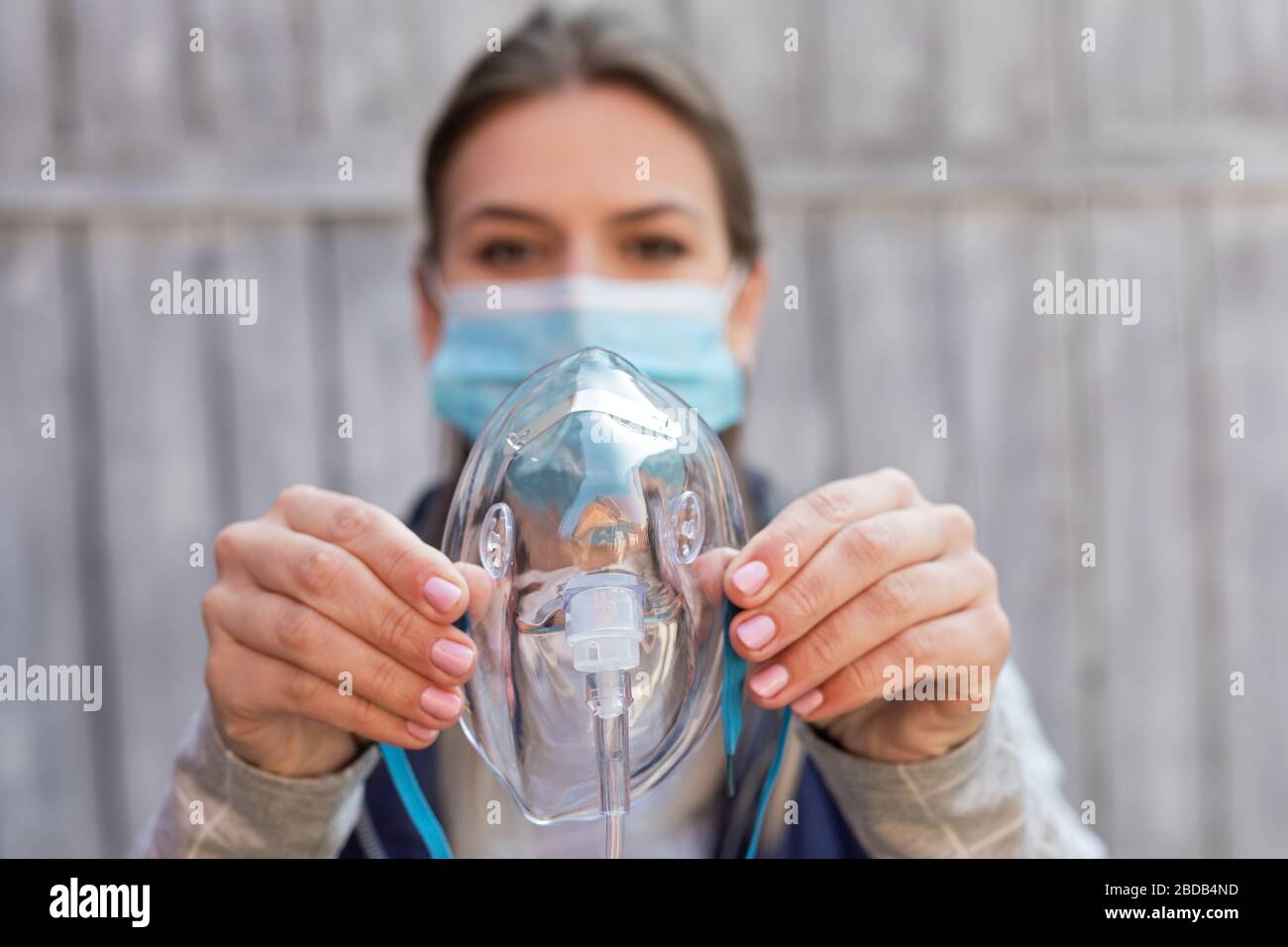 Woman wearing surgical mask is holding a medical oxygen mask outside ...