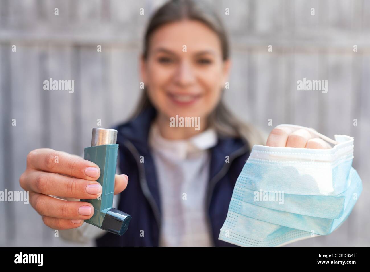Beautiful young woman holding asthma inhaler and surgical mask outdoor ...