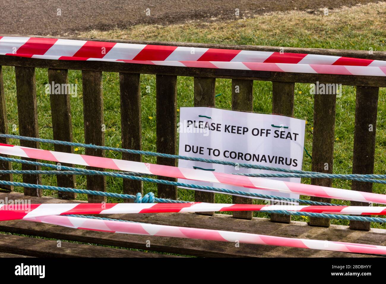 Park bench with sign not to sit on and white and red warning tape ...