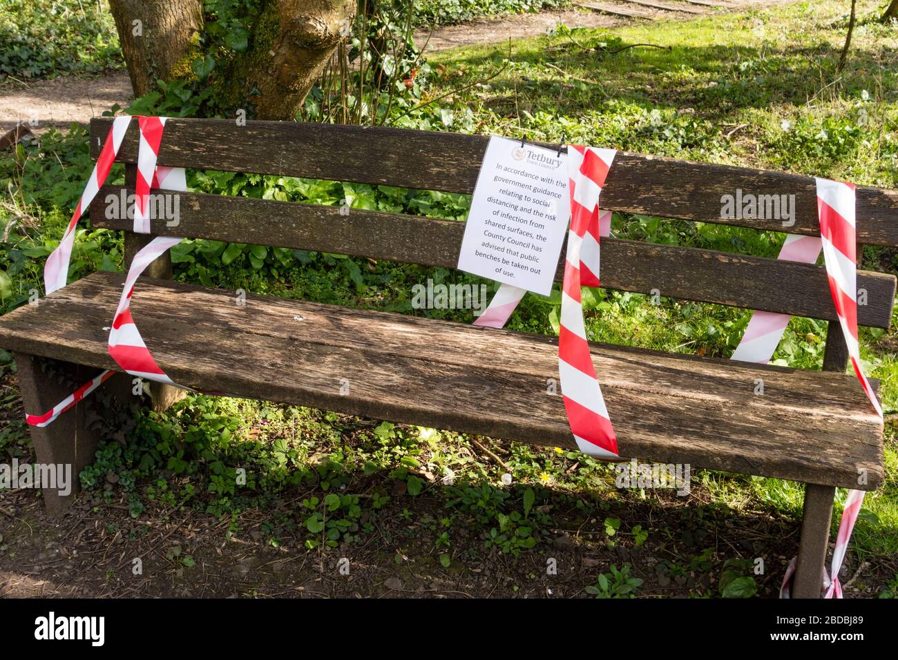 Park bench with sign not to sit on and white and red warning tape ...