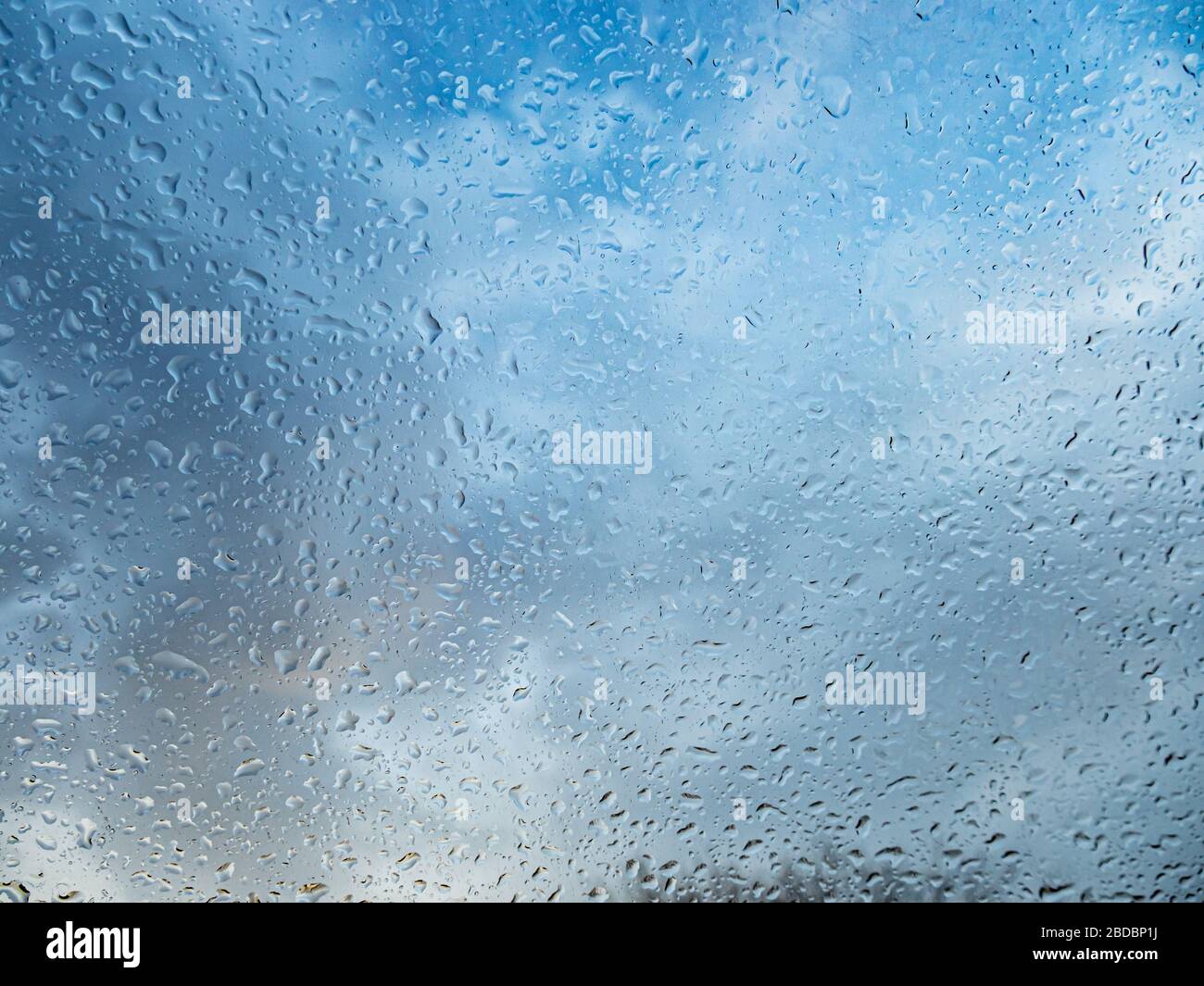 Wet window with rain drops and a cloudy sky outside background Stock ...