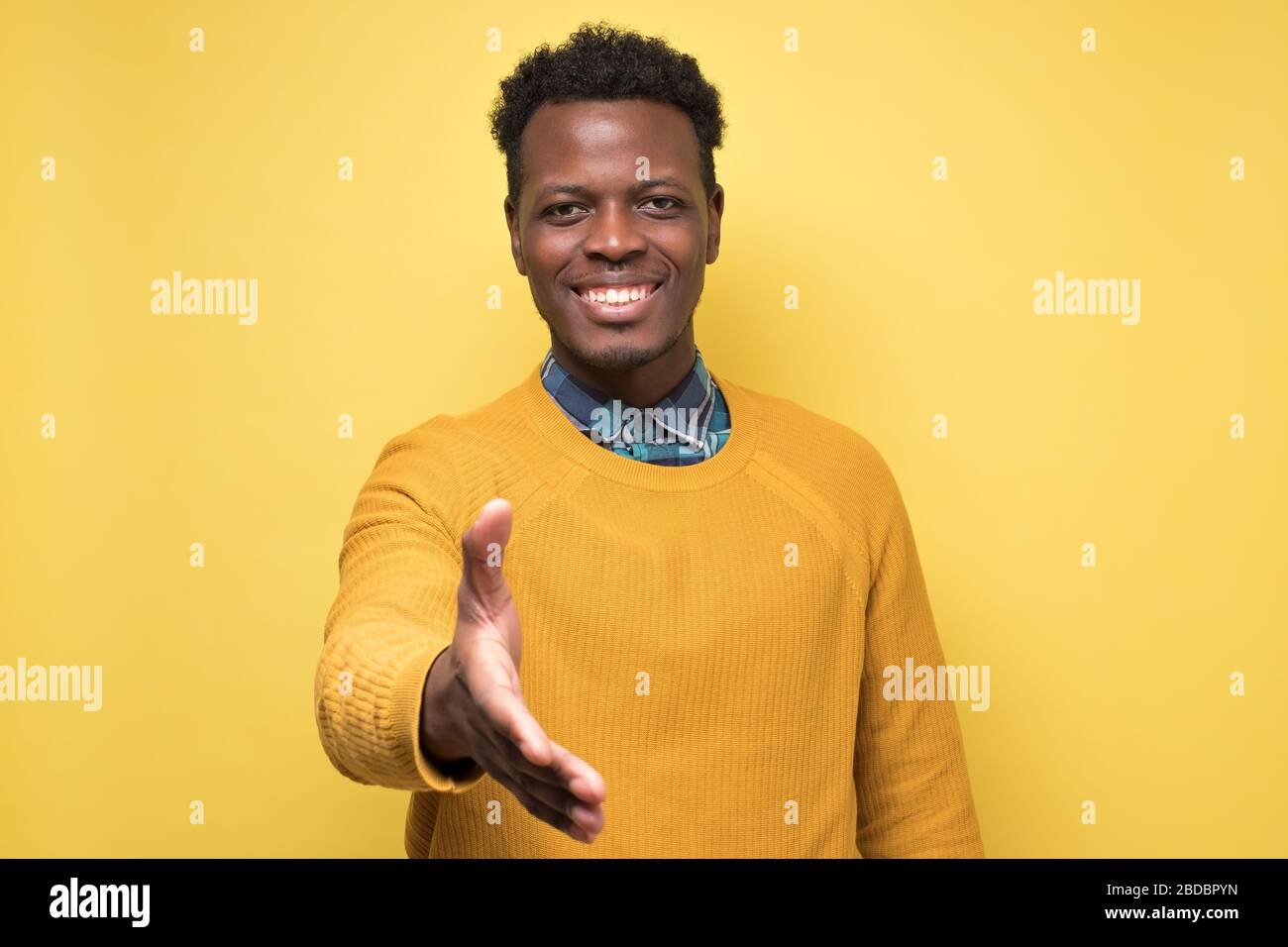Black male reaching out toward camera to shake hands on yellow ...