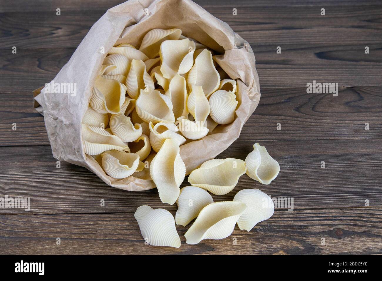 Pouch bag with pasta conchiglie flatlay, top view. Packaging on dark ...