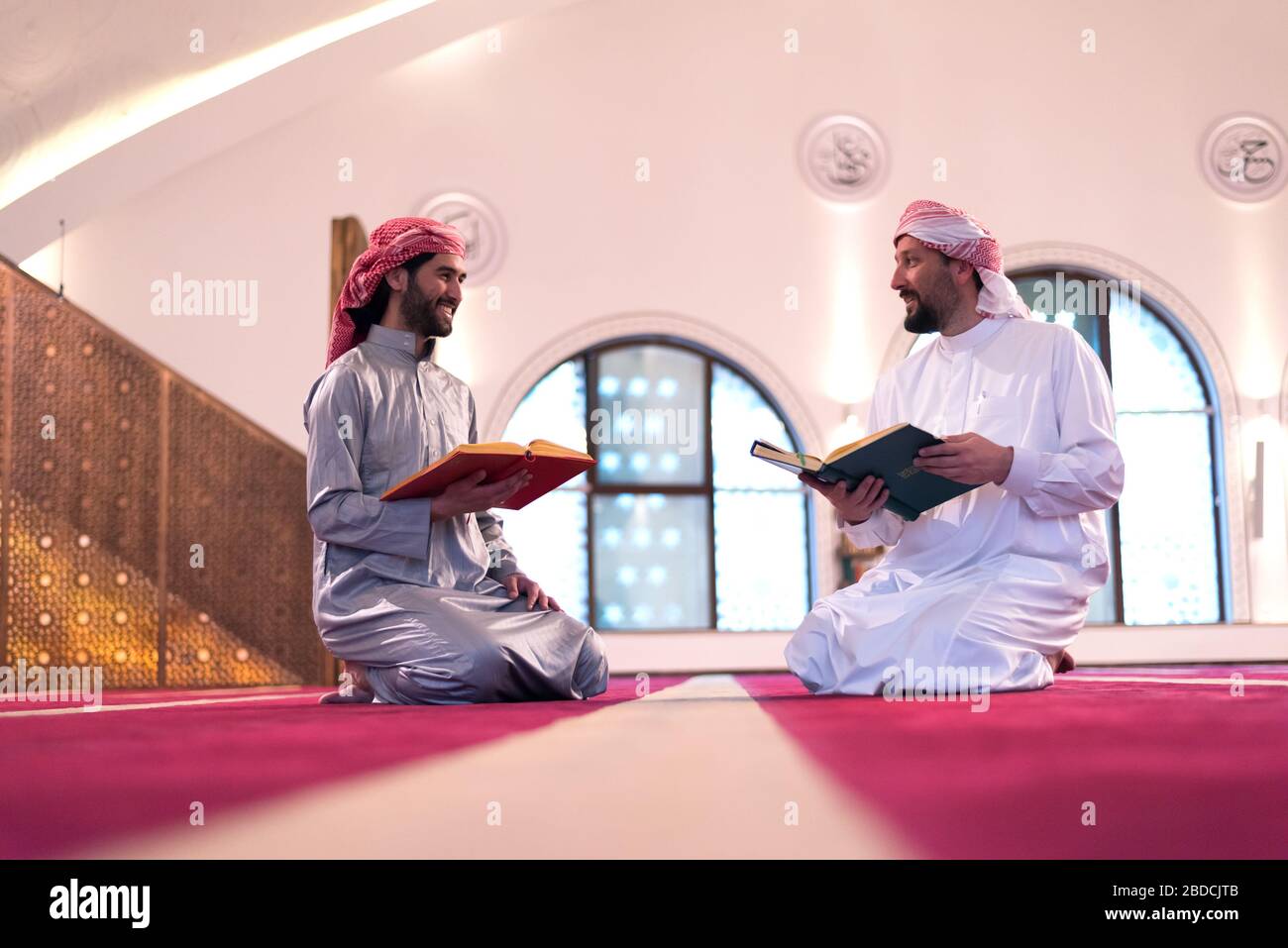 Two muliethnic religious muslim young people praying and reading Koran ...
