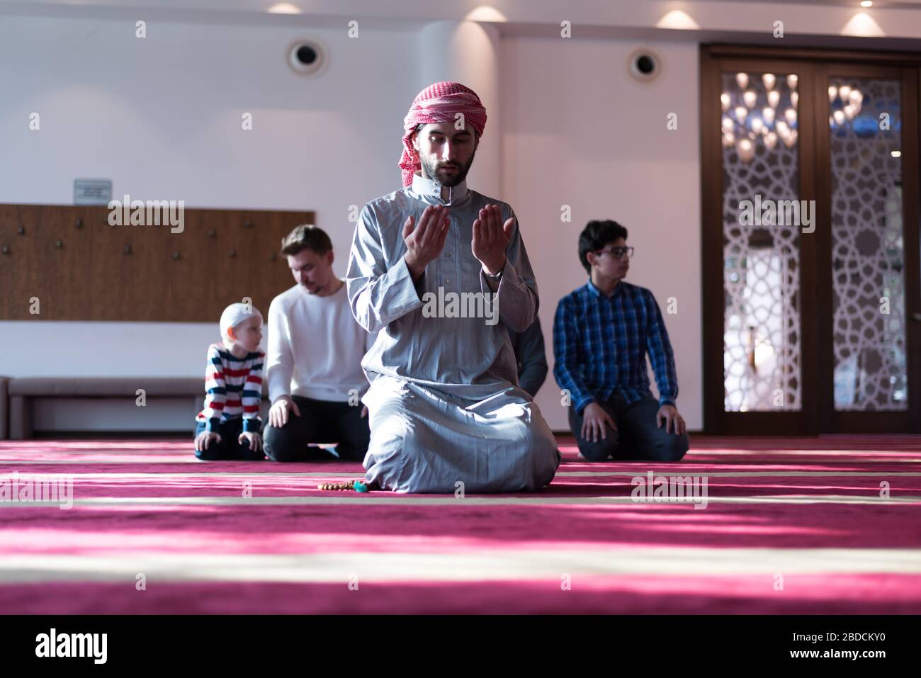 Group of muliethnic religious muslim young people praying and reading ...