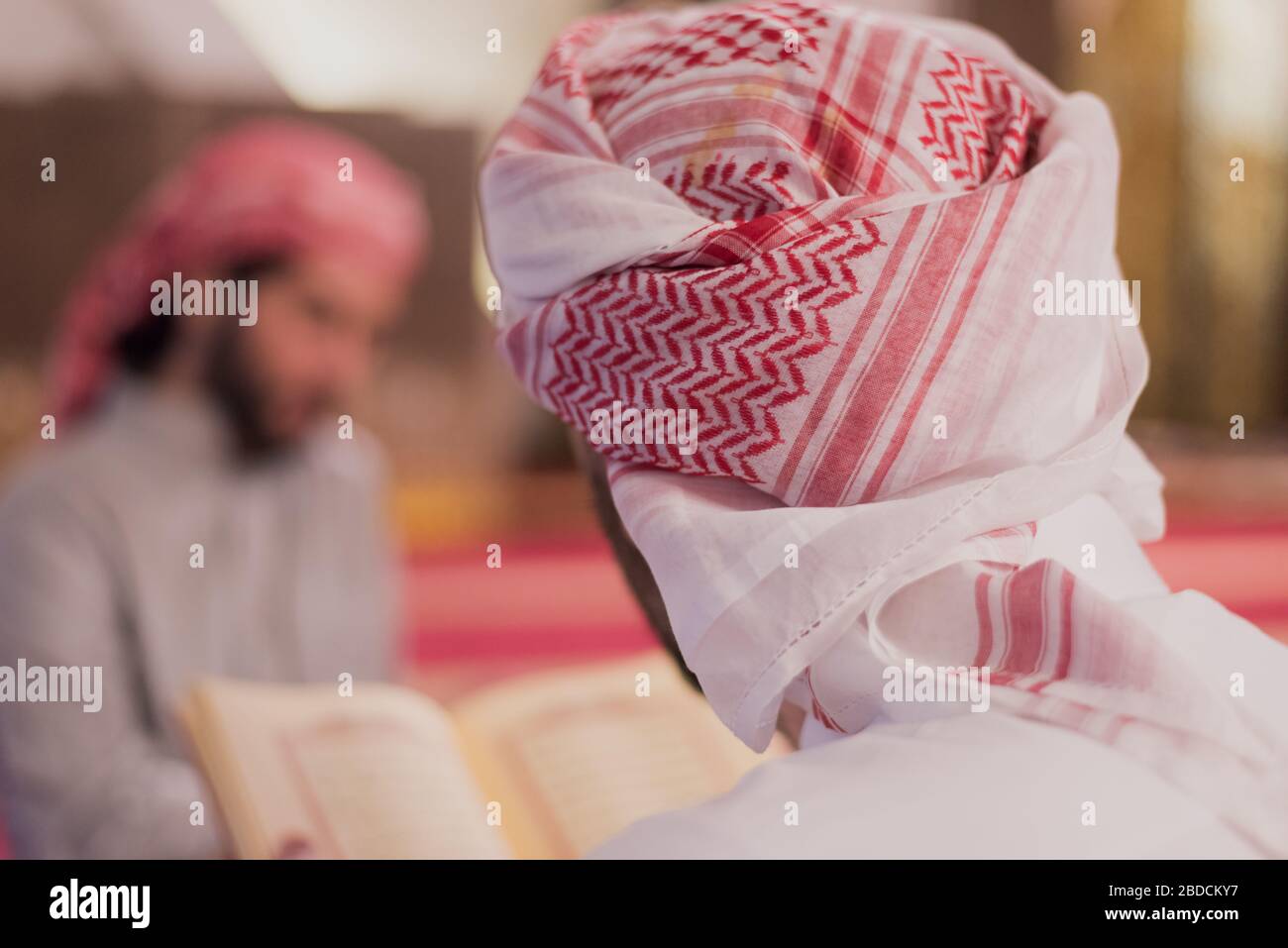 Two muliethnic religious muslim young people praying and reading Koran ...