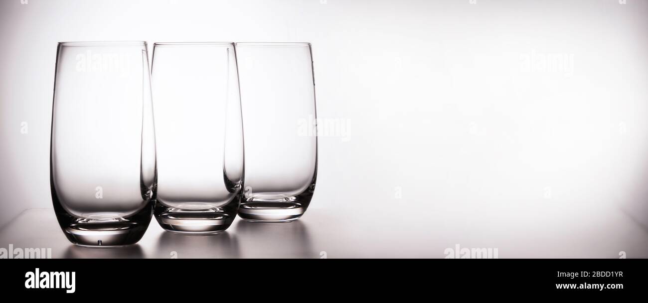 three empty glass glasses on a white background. Close up. long layout ...