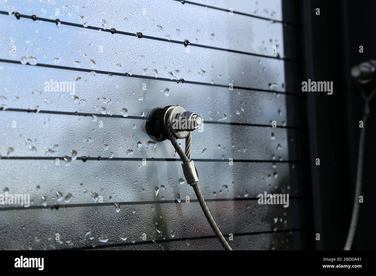 Glass fixed with a metal cable and bolt with nut Stock Photo - Alamy