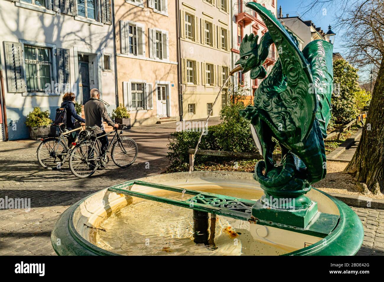 People passing a water fountain in the shape of a basilisk, the ...