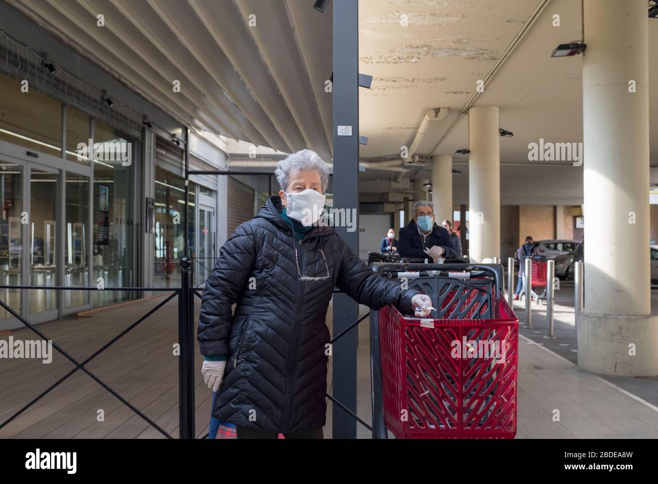 These people are lined up waiting to get into a supermarket. Guards are ...