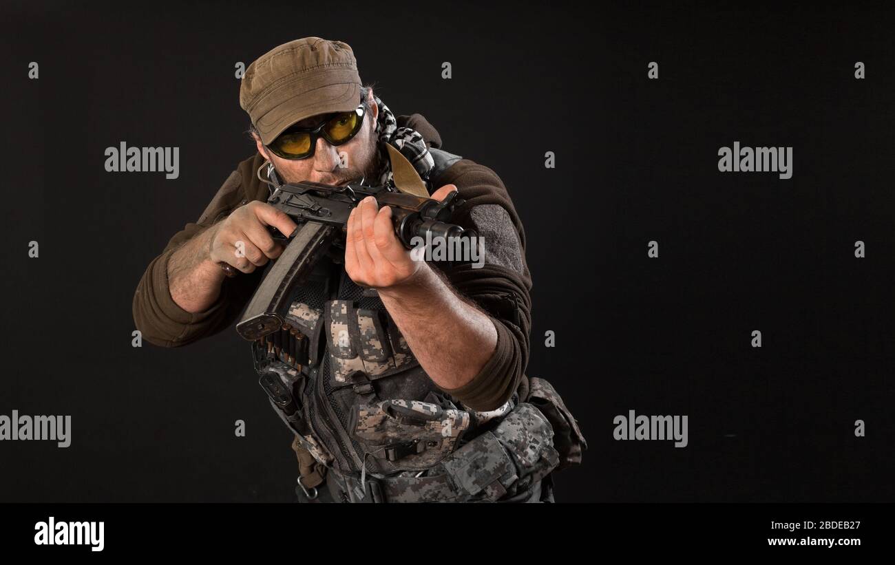 A mercenary with a gun aims at the enemy. Close-up on a dark background ...
