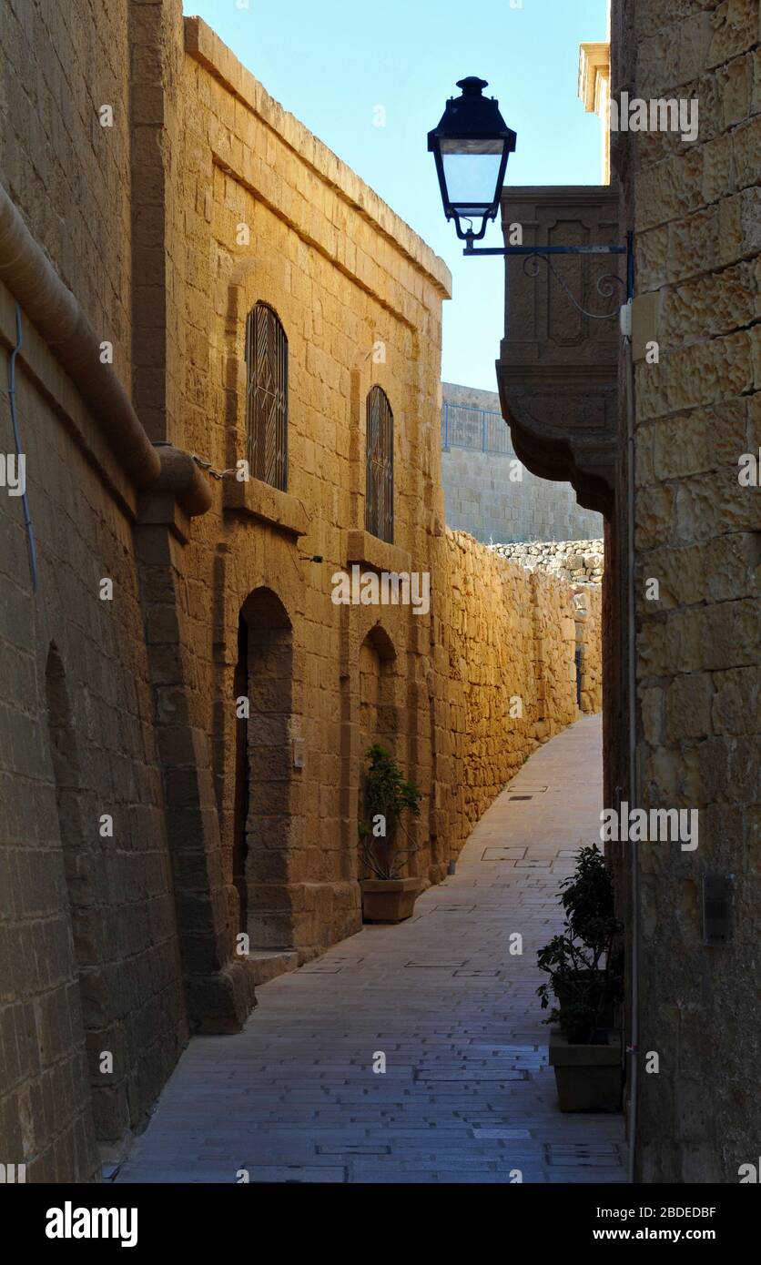 Stone buildings on a quiet path lit by the setting sun in the historic ...