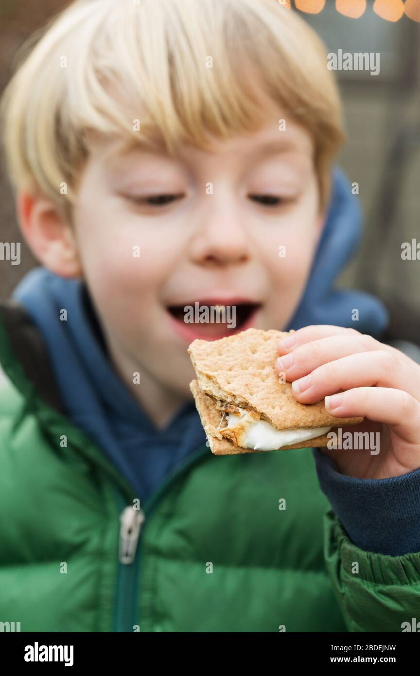 Cute boy (4-5) eating cracker with marshmallow Stock Photo - Alamy
