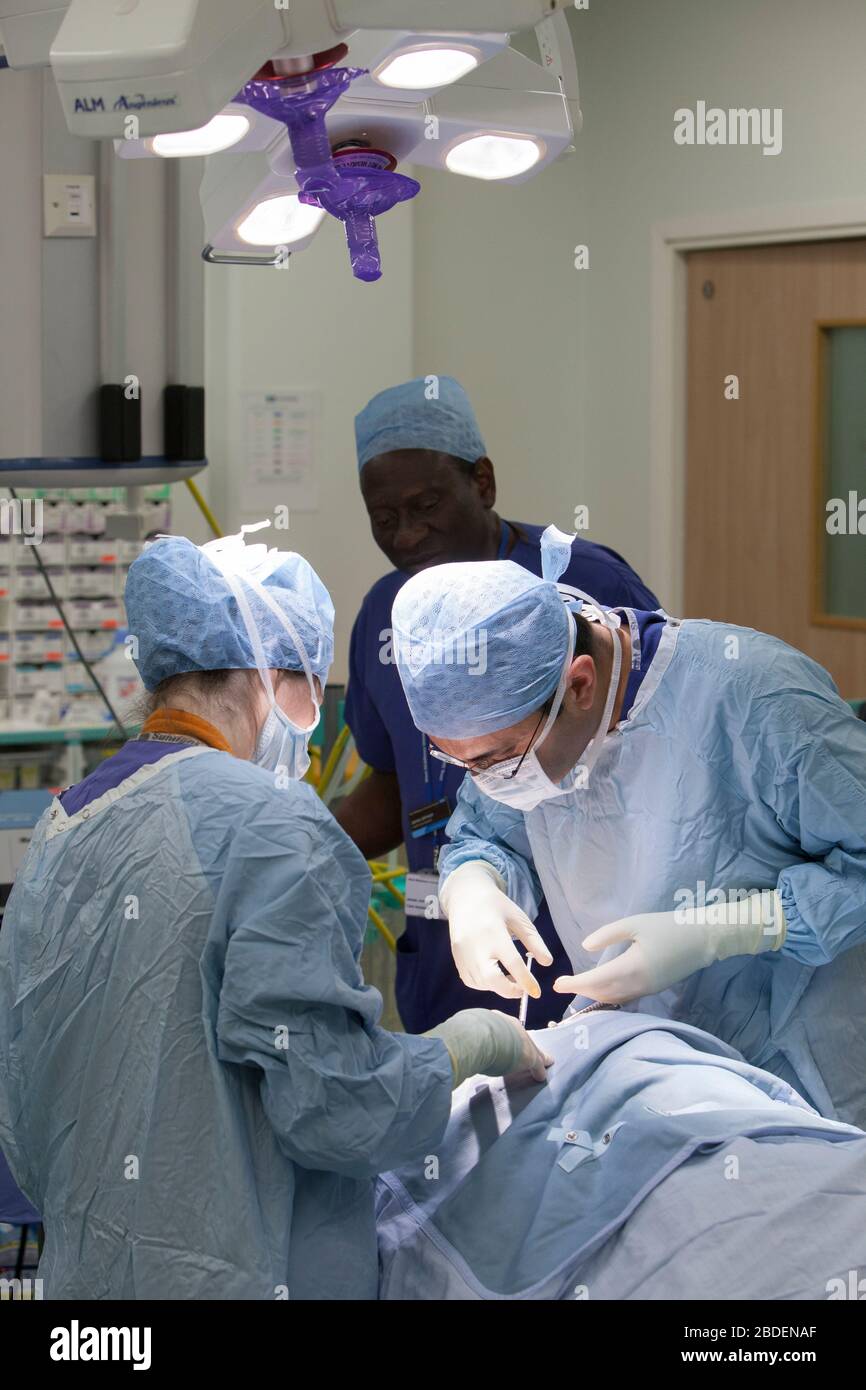 Surgeons and nurses perform stomach surgery in an NHS hospital. The NHS ...