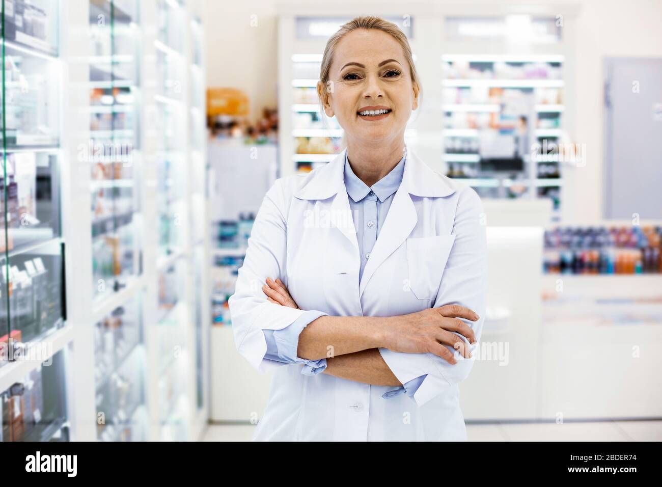 Positive female pharmacist looking contented and smiling Stock Photo ...