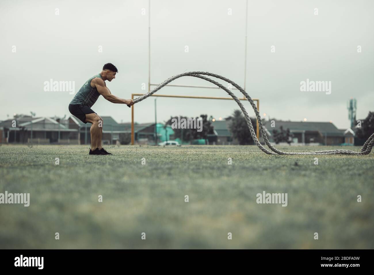 Fitness man using training ropes for exercise outdoors at a ground ...
