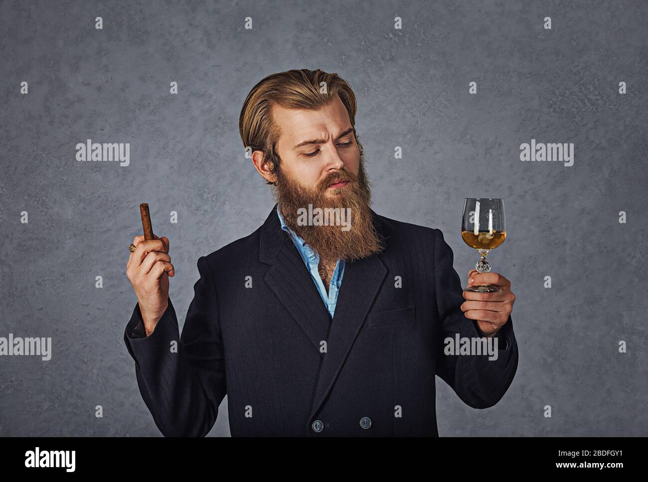 Young handsome bearded caucasian man sommelier tasting cognac with a ...