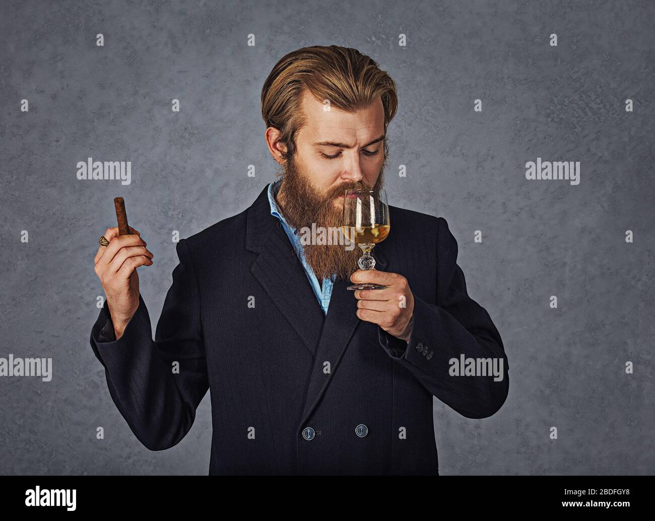 Young handsome bearded caucasian man sommelier tasting cognac with a ...