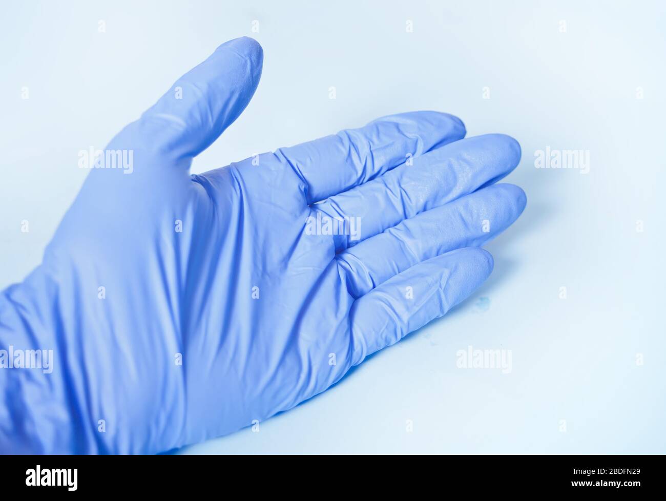 Woman doctor hand in a blue gloves on the blue background. Medical ...